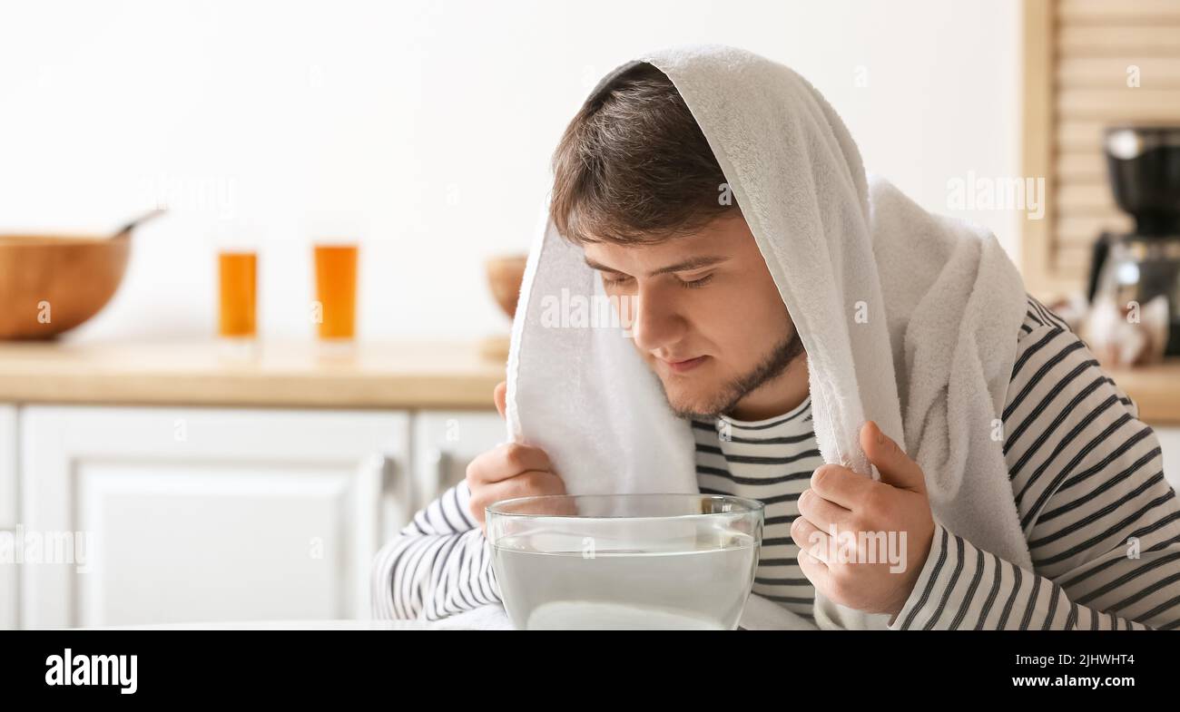 Young man doing steam inhalation at home to soothe and open nasal ...