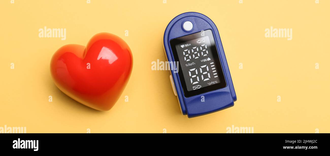 Red heart and pulse oximeter on yellow background Stock Photo - Alamy