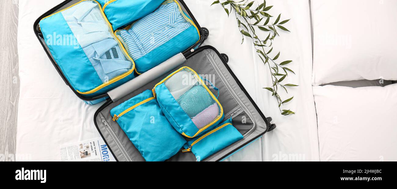 Open packed suitcase on bed in room Stock Photo - Alamy