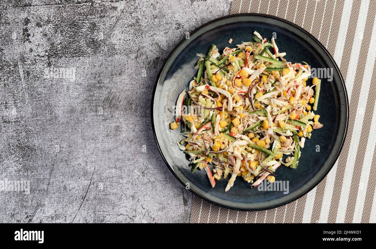 Tuna salad with surimi crab sticks, corn and cucumber on a round plate ...