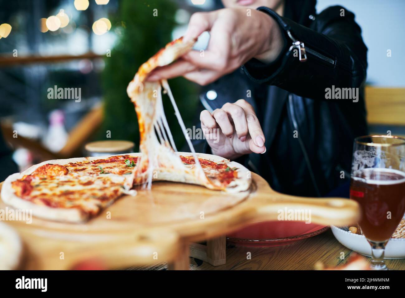 A woman takes a slice of pizza at a pizza parlor. Pulling cheese, yummy ...
