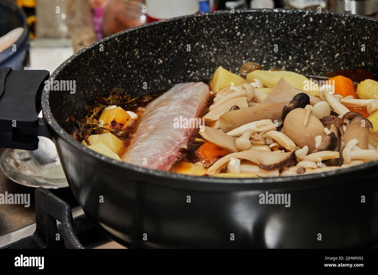 Fish stewed with carrots, mushrooms and potatoes is fried in pan on gas ...