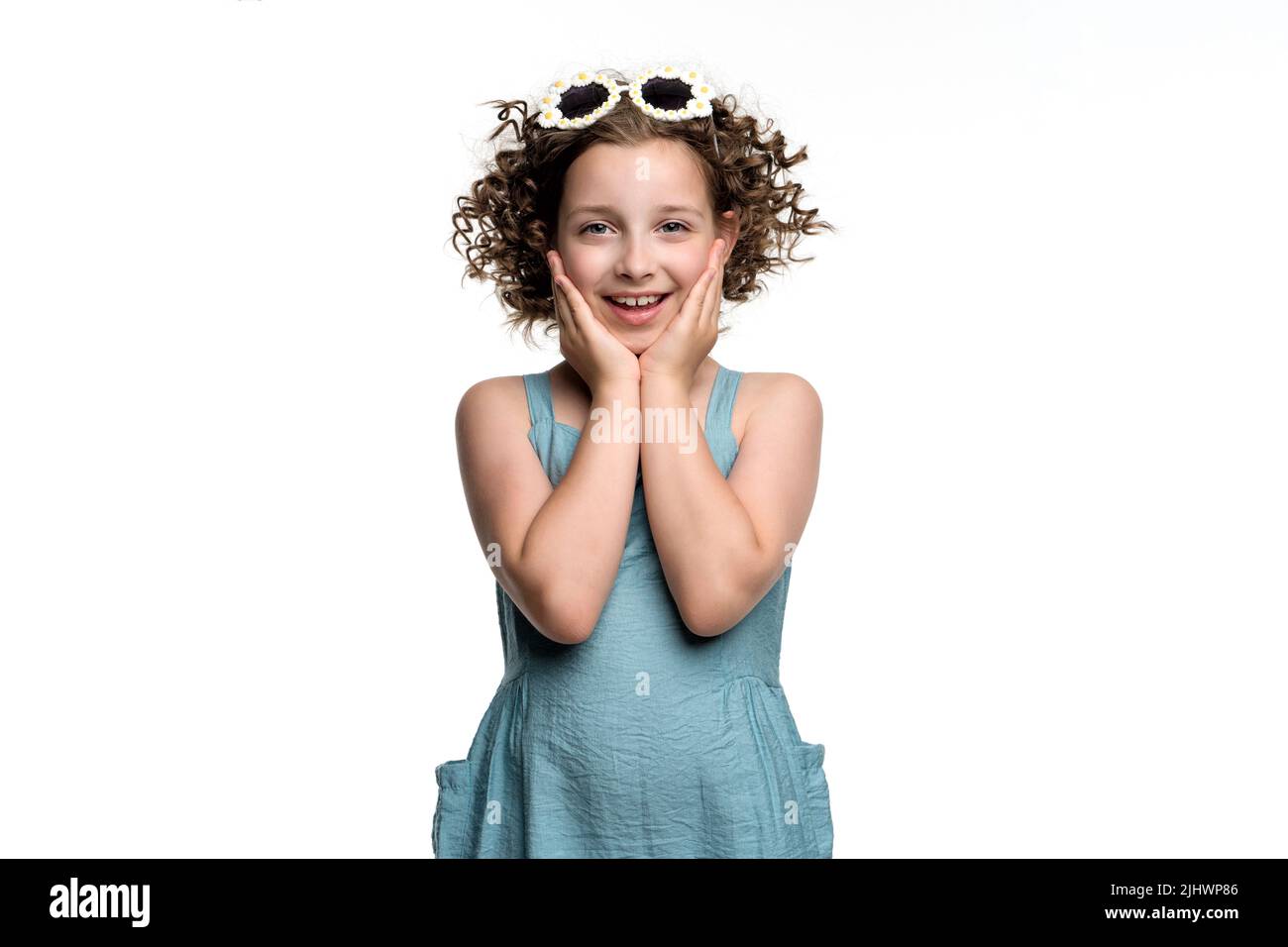 Surprised cute curly short-haired girl 10-12s in blue summer sundress ...