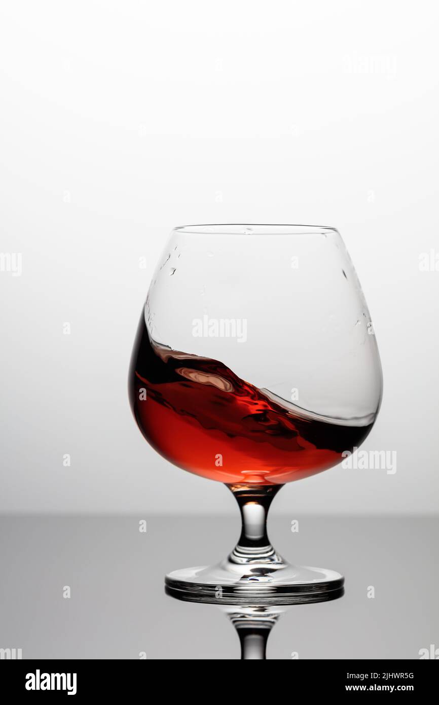 Splash of brandy in a snifter glass. Copy space Stock Photo - Alamy