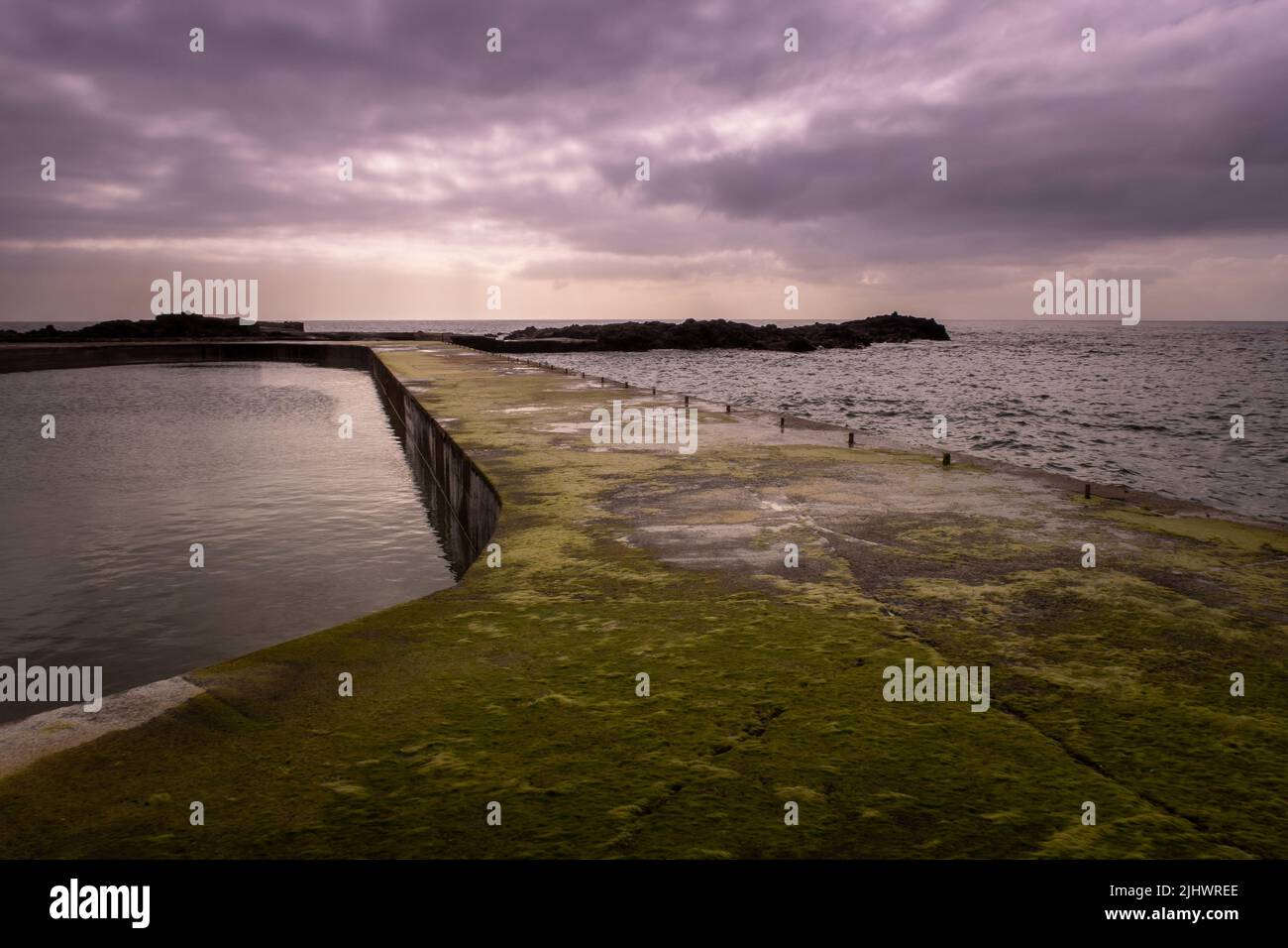 A beautiful view of a lonely dock under the cloudy sky at sunset Stock ...