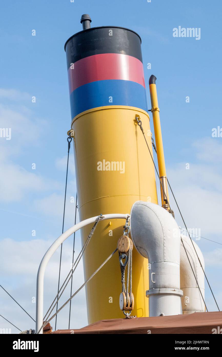 A vertical shot of a colorful metal water tube on a ship in cloudy sky ...