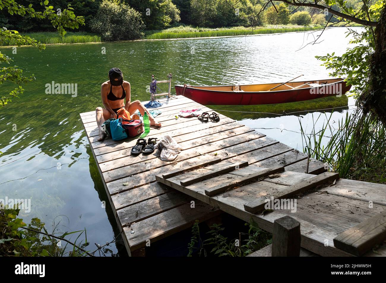 Woman tourist preparing lunch on a wooden pier, exploring Krka river ...