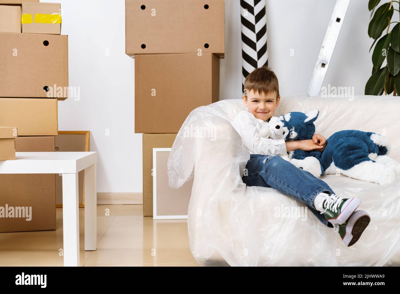 Little boy sitting on sofa with boxes on a moving day Stock Photo - Alamy