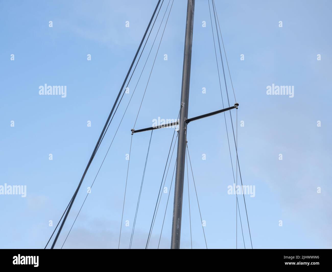 Yacht mast with ropes with blue sky in background Stock Photo - Alamy