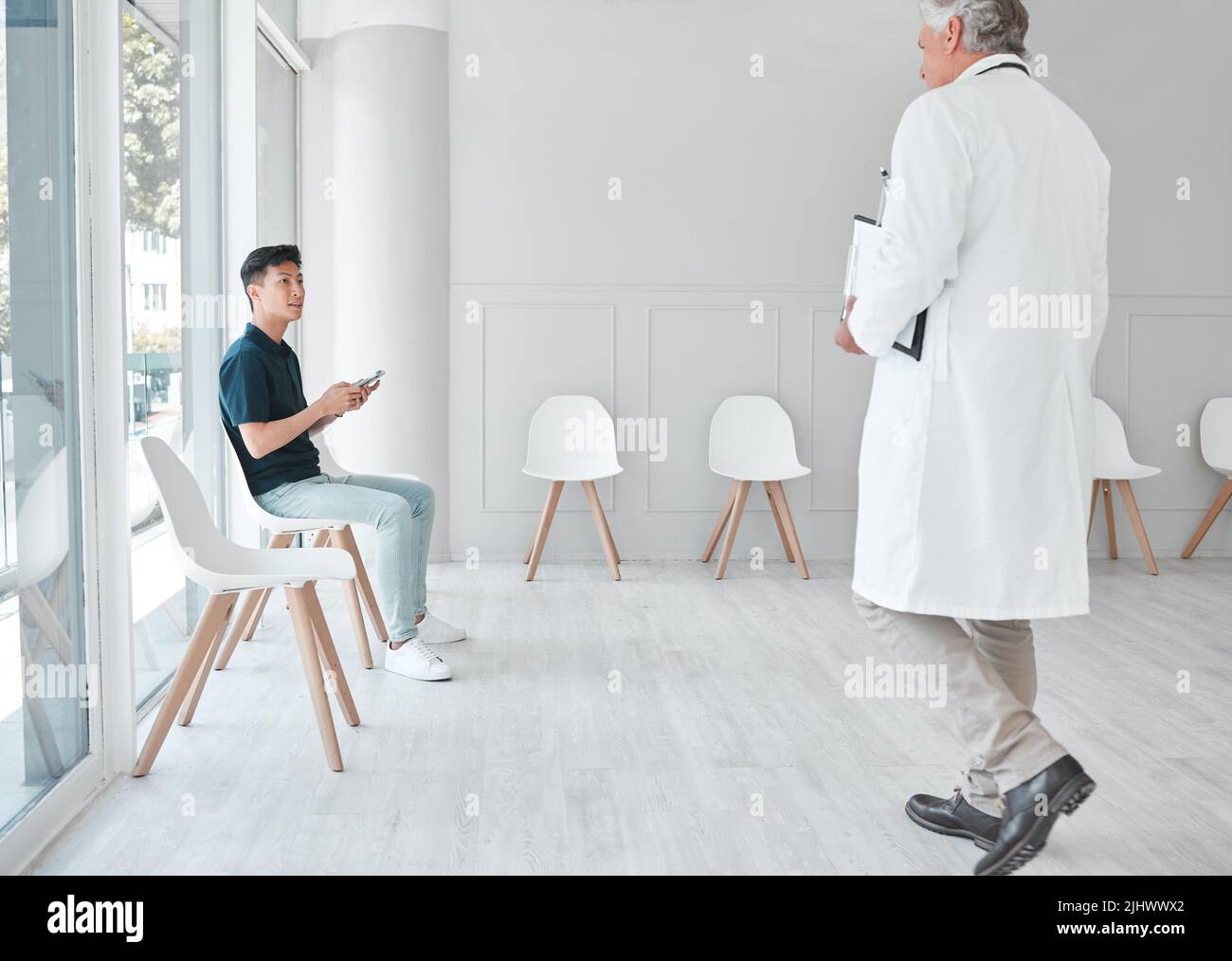 Its my turn now. a young man using a cellphone while sitting in the ...