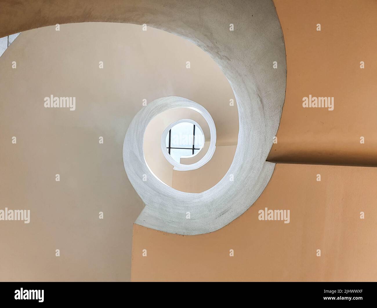 A low angle shot of a spiral concrete staircase with a window at the ...