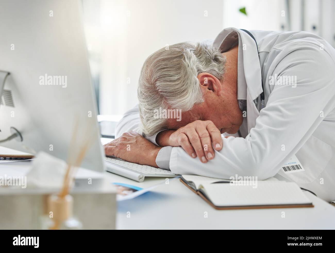 Getting a quick nap in. a mature doctor sleeping at his desk at work ...