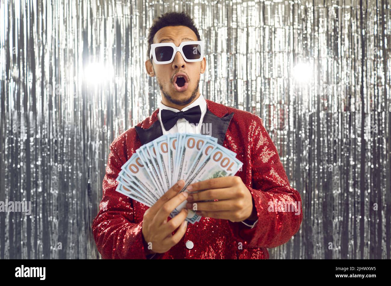 Happy surprised young guy who has won cash prize is holding bunch of ...