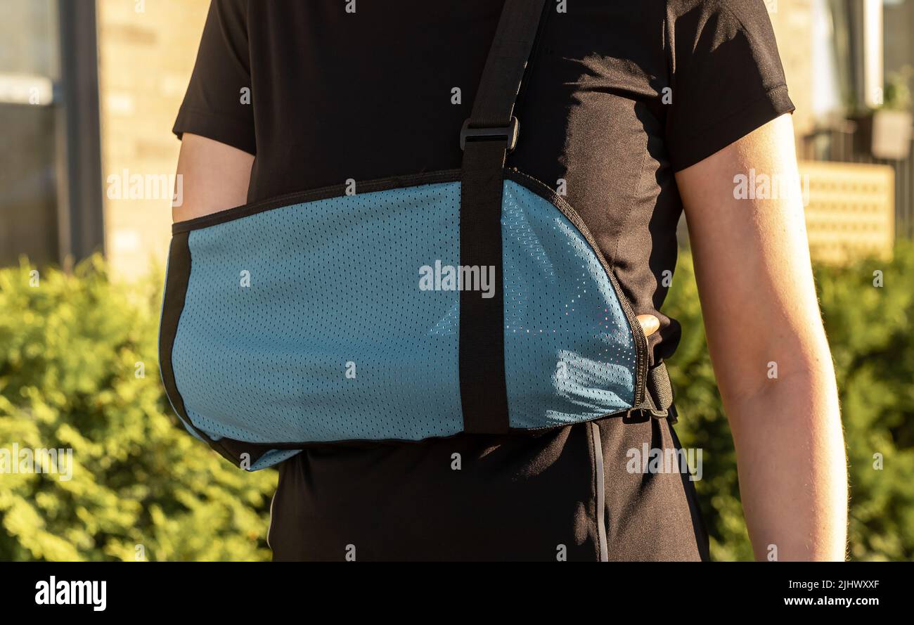 Woman wearing sling to protect injured arm. Elbow, shoulder, forearm ...