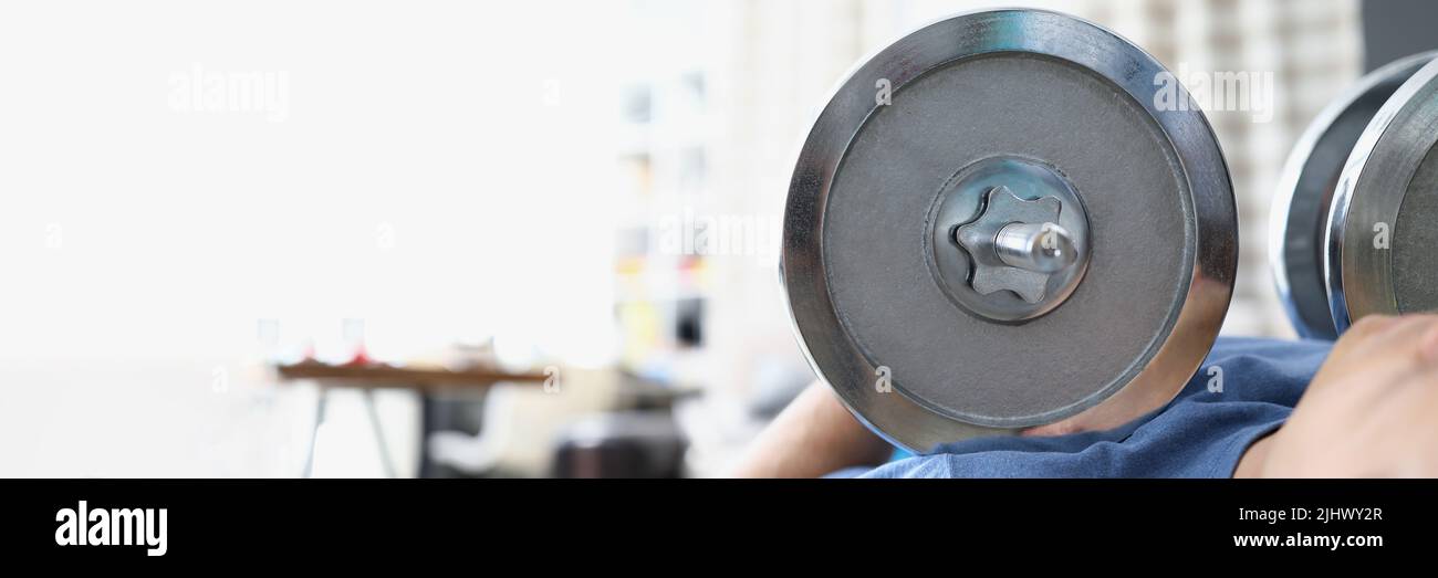 Man lift heavy metal dumbbell laying on training machine Stock Photo ...