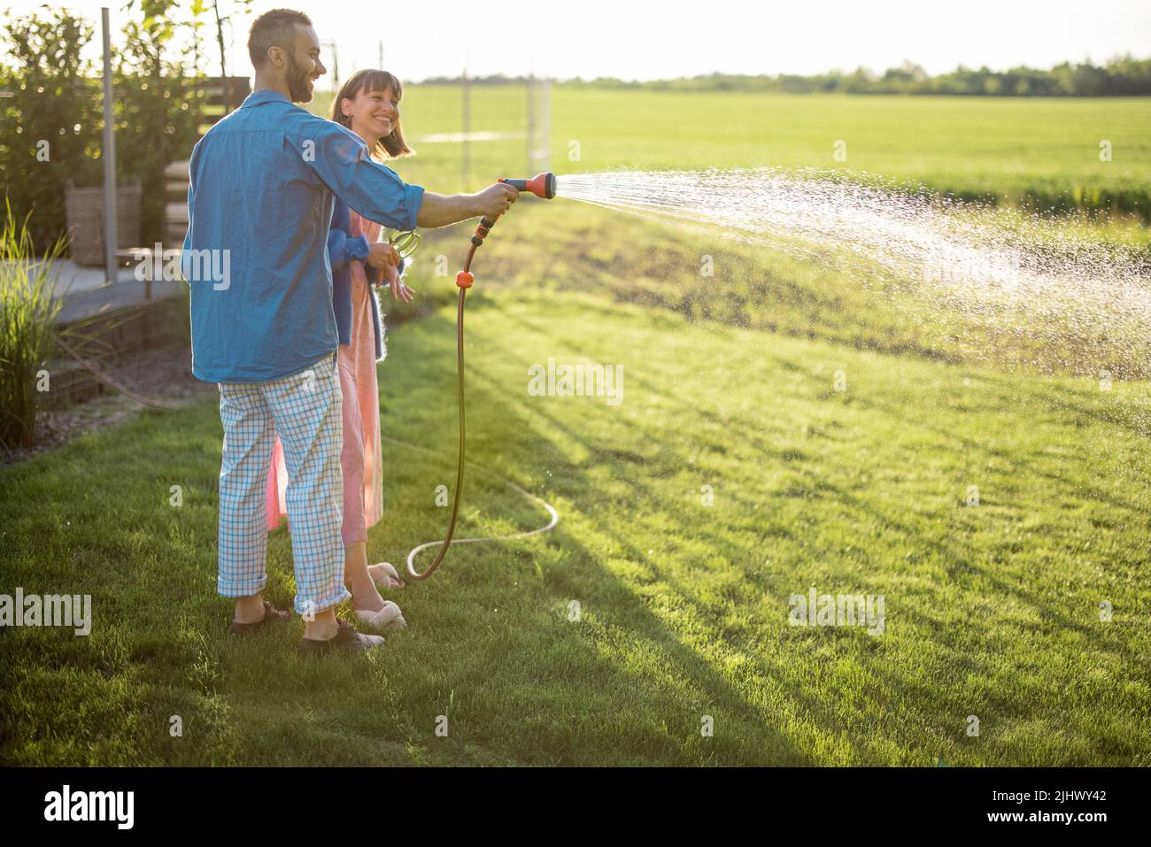 Lovely couple watering lawn at backyard Stock Photo - Alamy