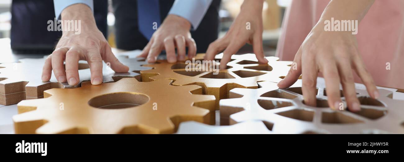 Business people making whole picture of wooden gears on workplace ...