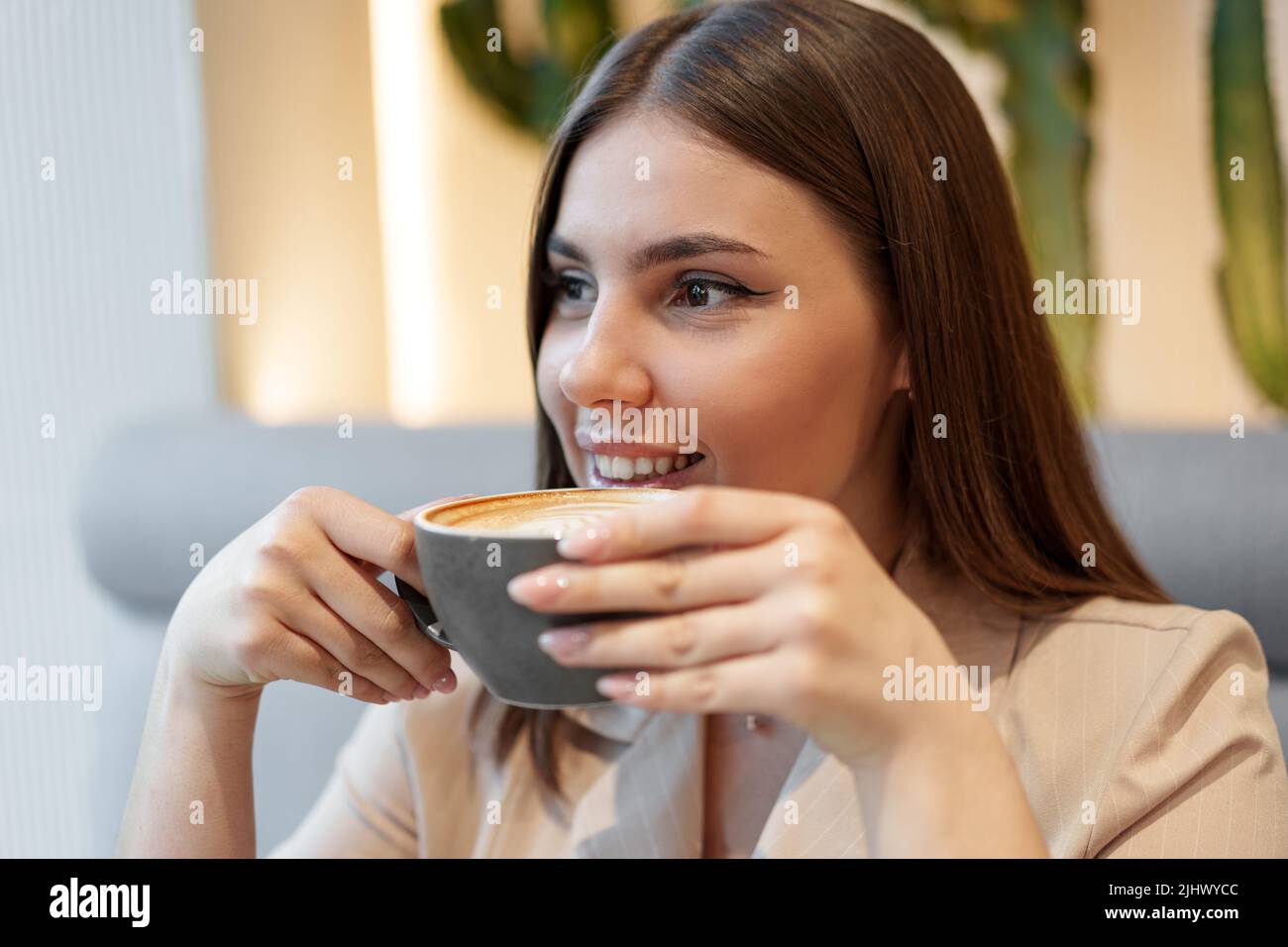 Young woman drinking coffee in a cafe Stock Photo - Alamy