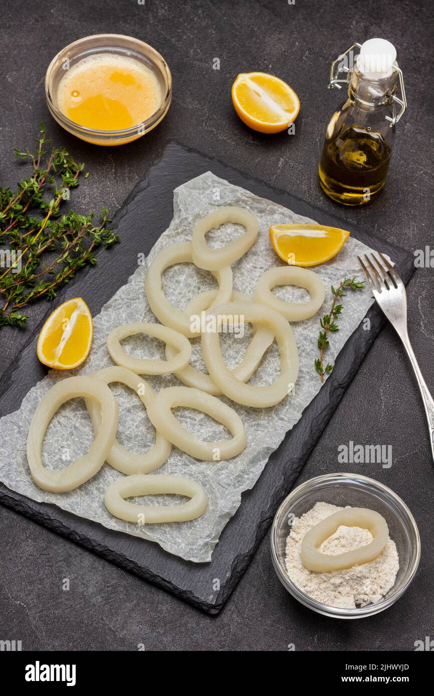 Squid cut into rings on stone board. Fork and oil in bottle. Flour and ...