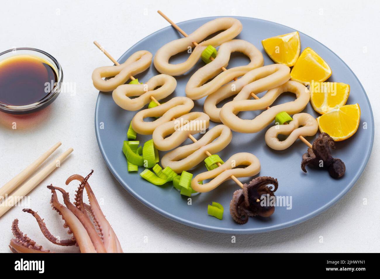 Squid tentacles, soy sauce in bowl. Squid rings, baby octopus on wooden ...
