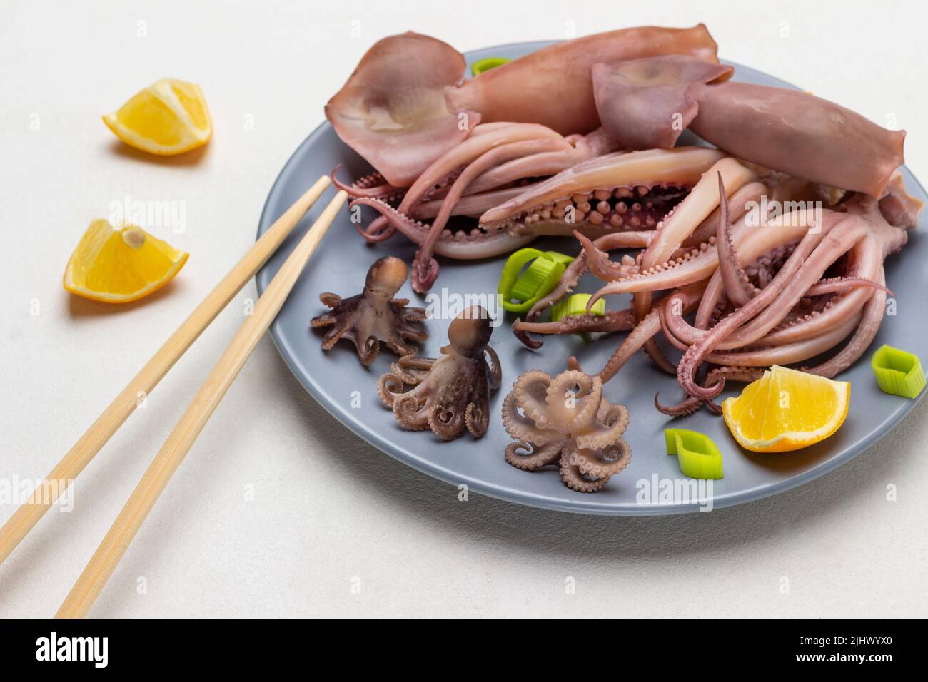 Boiled baby octopus and squid with tentacles on gray plate. Bamboo ...
