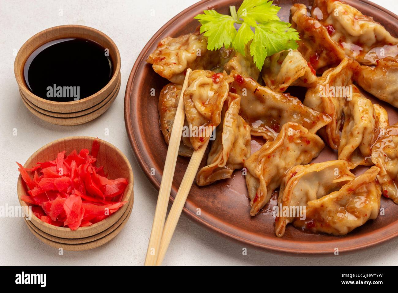 Gyoza dumplings and chopsticks on ceramic plate. Soy sauce and pickled ...