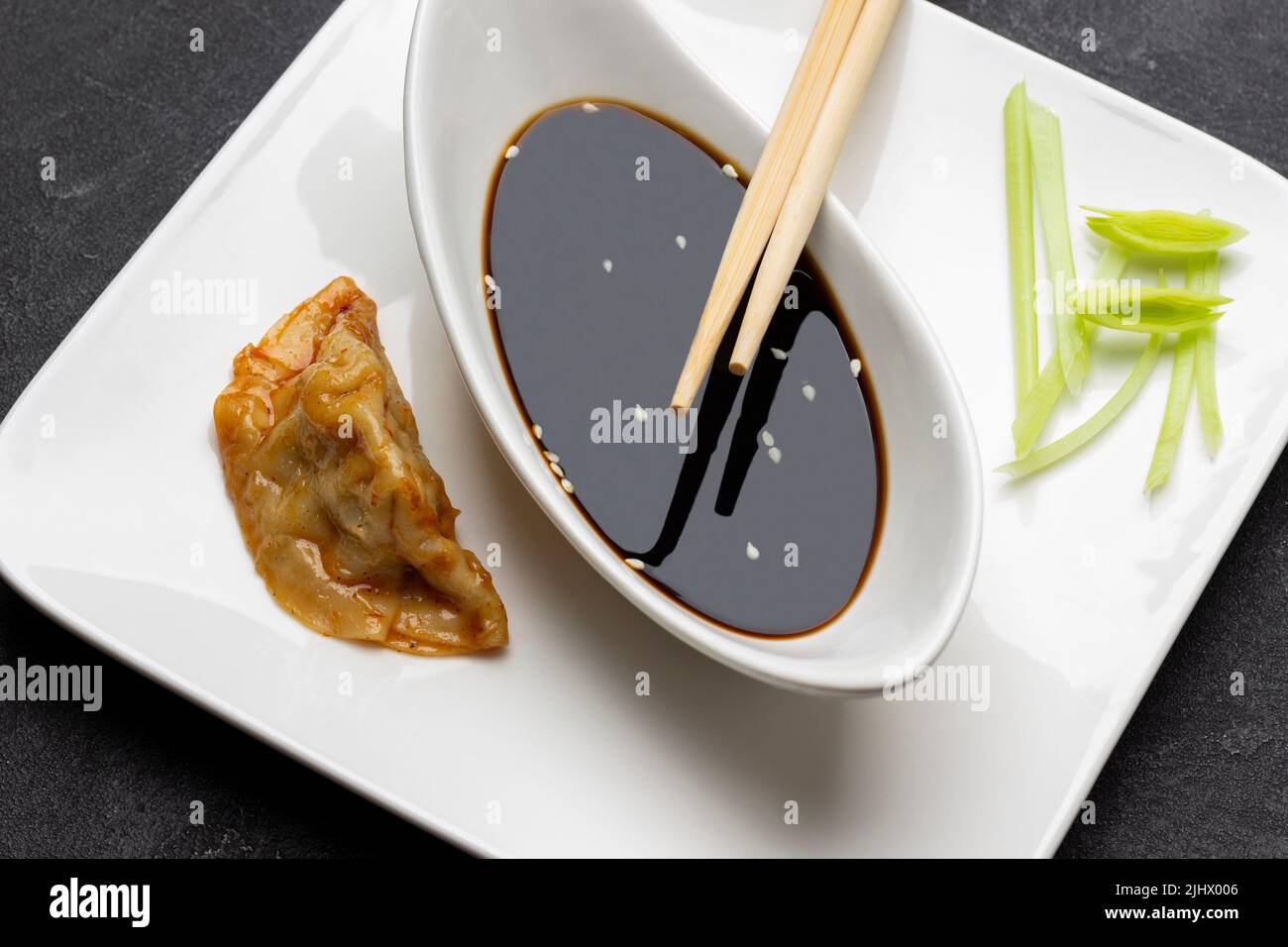 Soy sauce in bowl and chopsticks. Gyoza dumpling and leek on plate ...