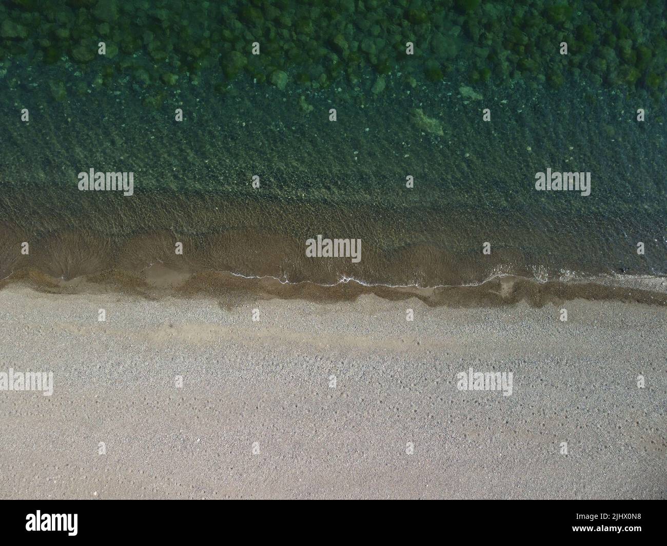 Aerial view on calm azure sea and volcanic rocky shores. Small waves on ...