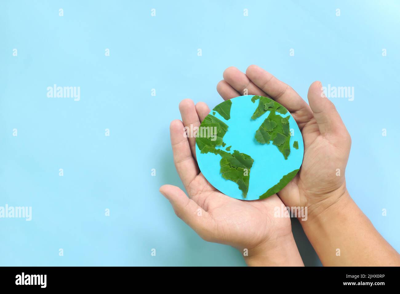Top view of human hand holding planet earth model with green leaves ...