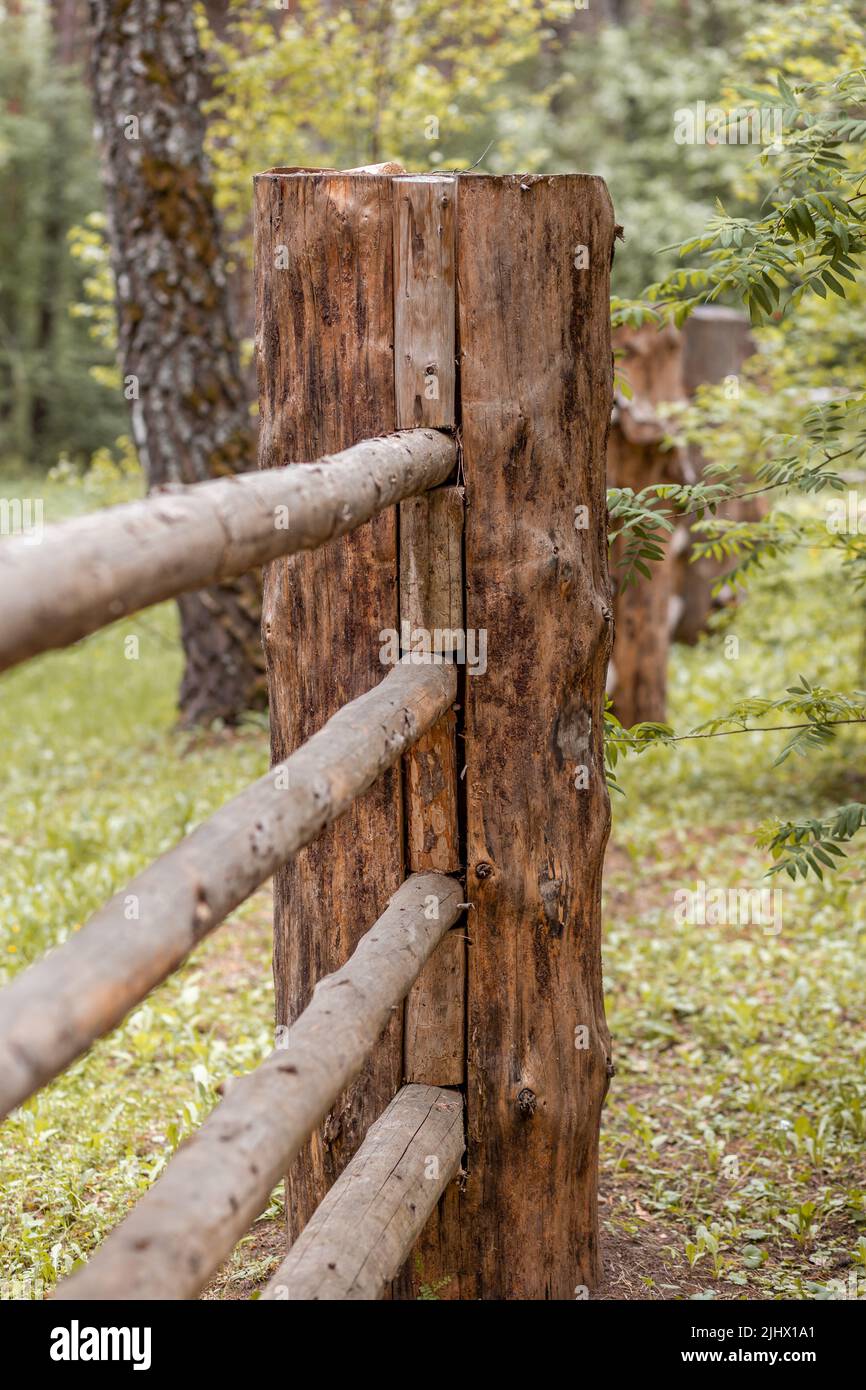 Large wooden fence posts that enclose an old wooden house in forest ...