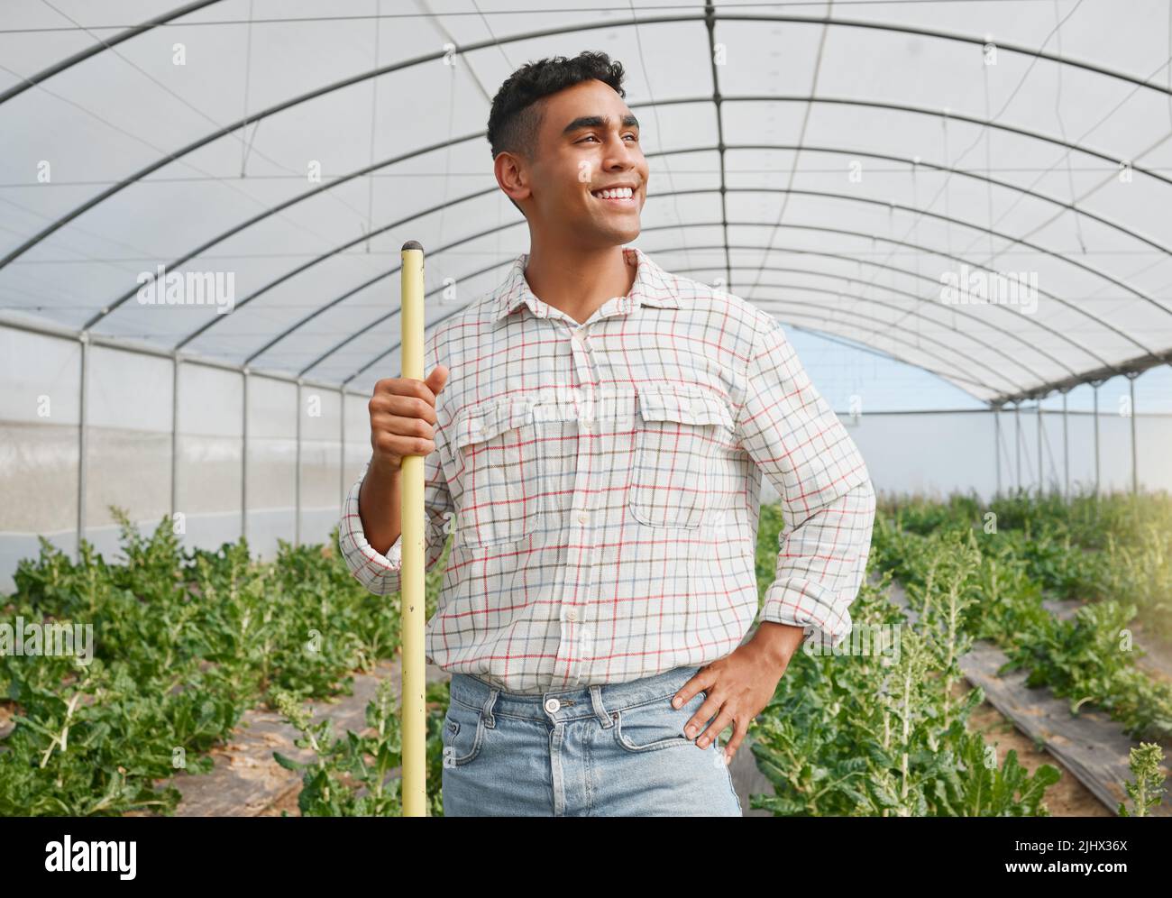 Getting his daily tasks done on time. a young man using a gardening ...