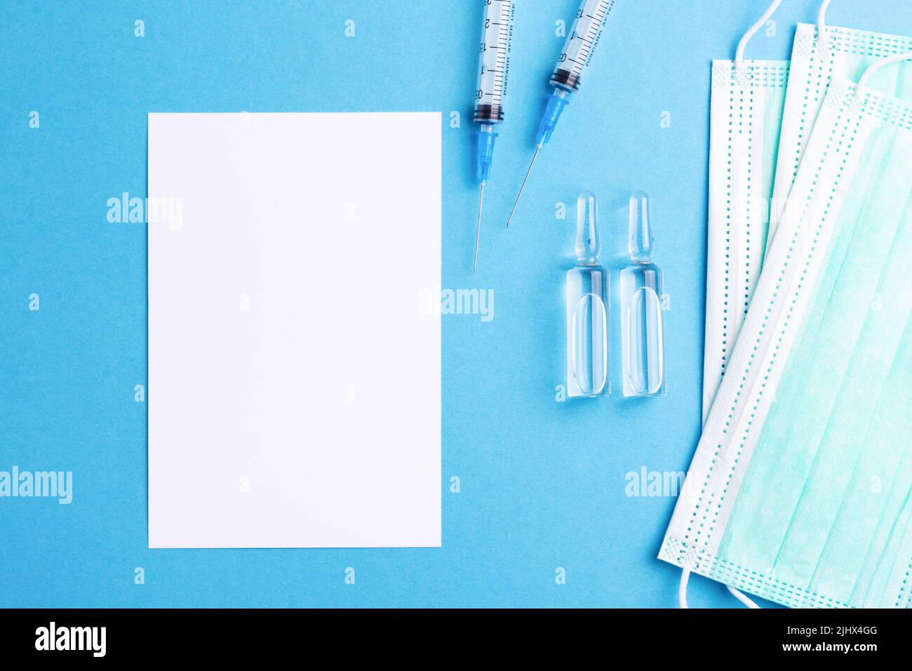 Medical flat lay with white empty paper card surrounded by vial liquid ...