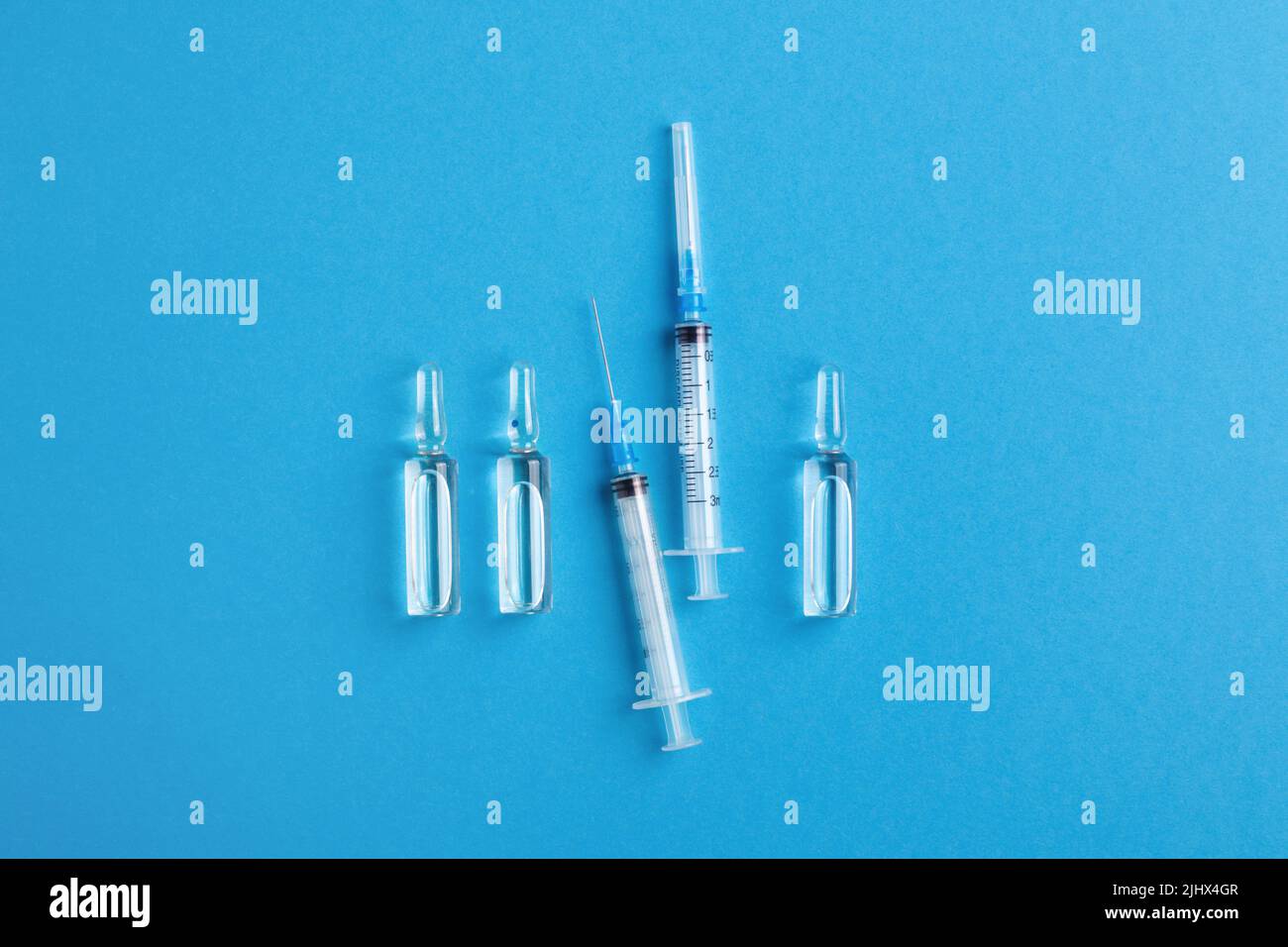 Medical glass vials and injection syringes isolated on blue background ...
