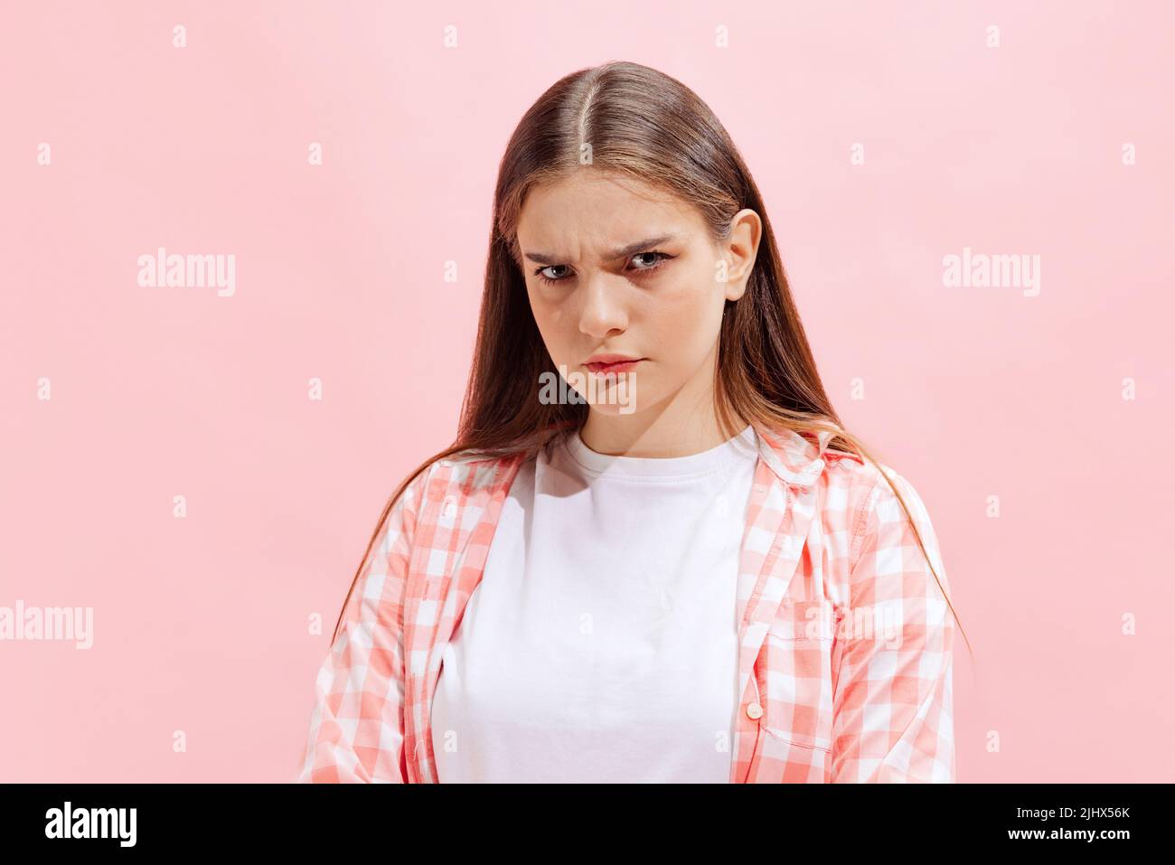 Portrait of emotive young girl in checkered shirt posing isolated over ...