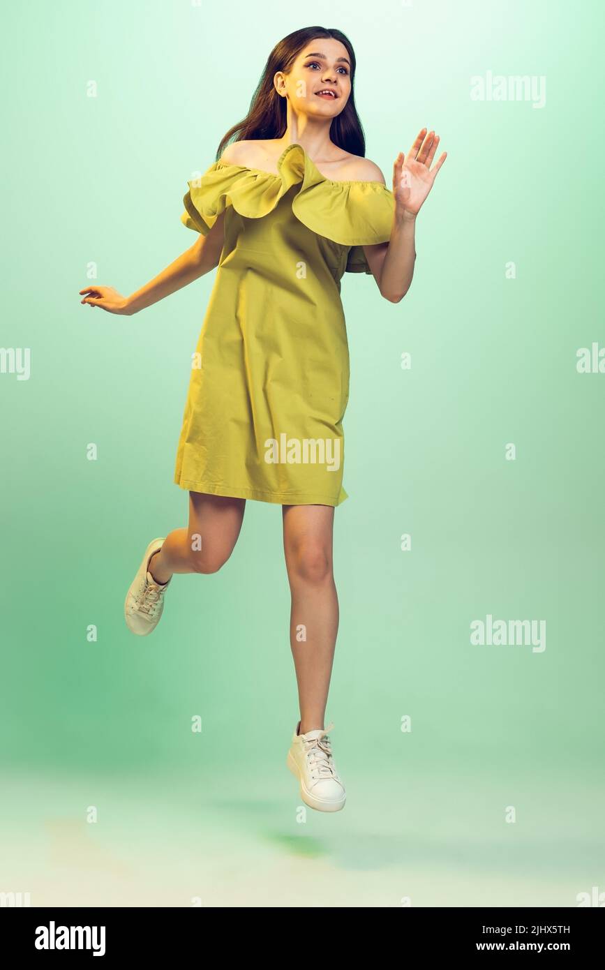 Portrait of young girl in stylish dress posing isolated over green ...