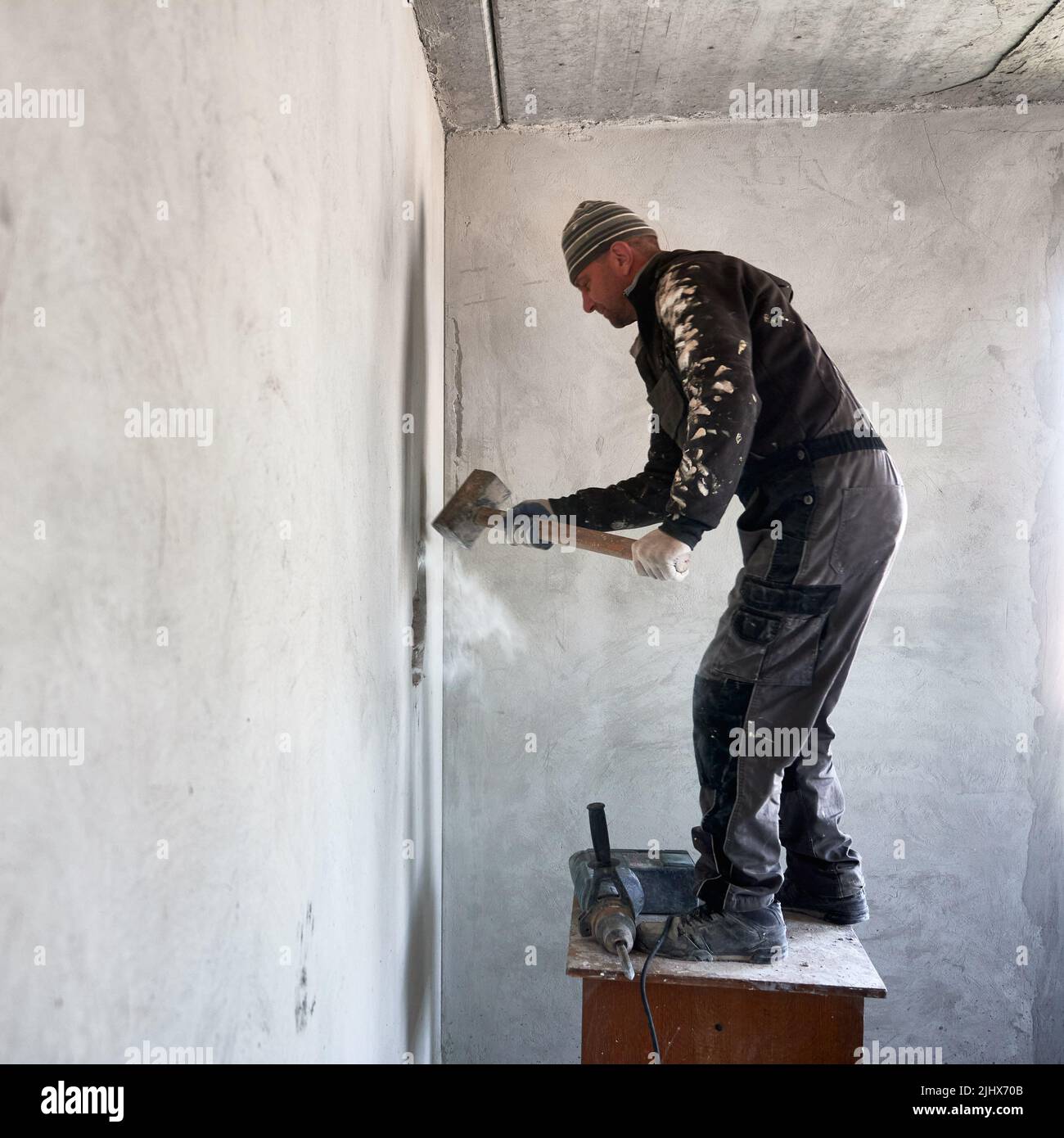 Full length of man builder standing on wooden desk and breaking the ...