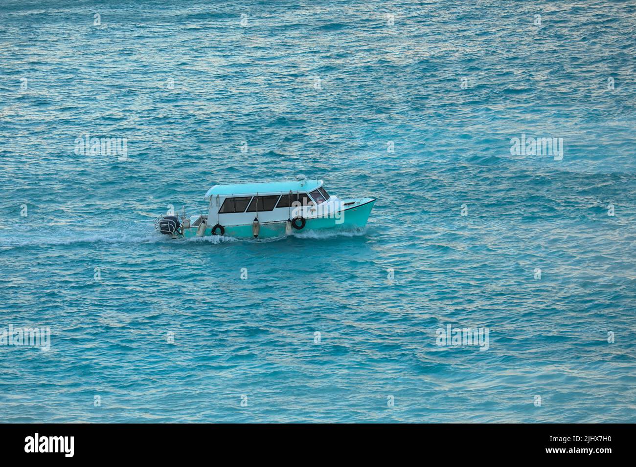 photo of small vessel cruising in tropical emerald clear sea Stock ...