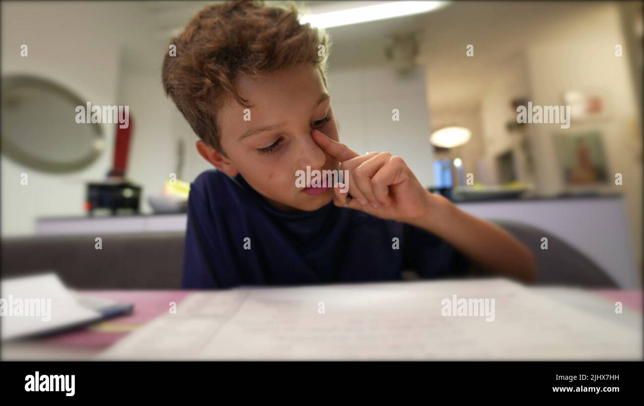 Kid doing homework holding pen writing notes Stock Photo - Alamy