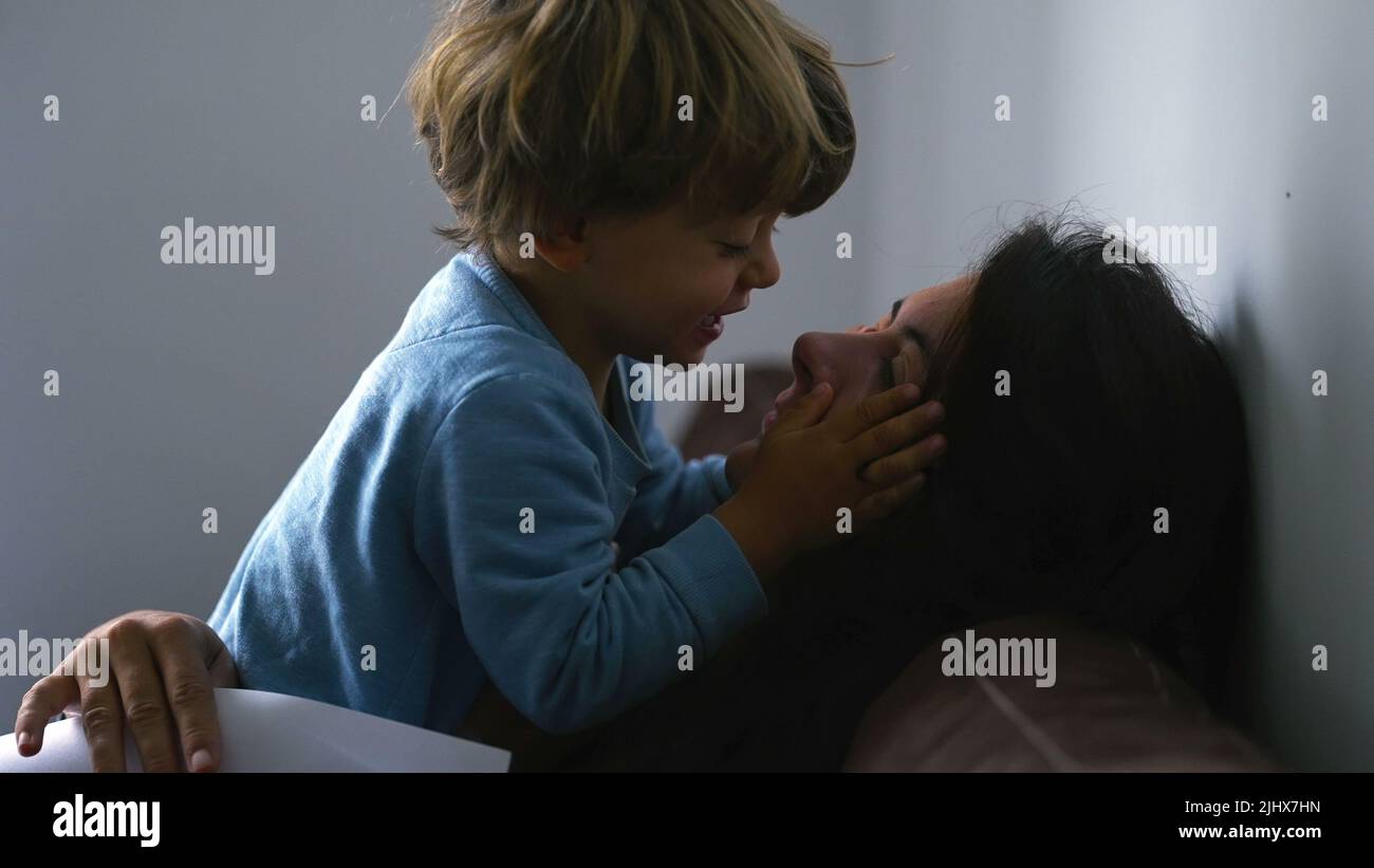 Little boy biting mother nose, real life authentic family moment at ...