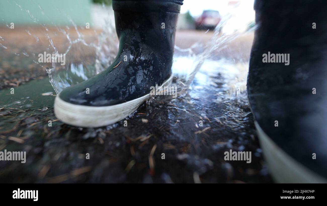 Kid jumps into puddle of water wearing boots Stock Photo - Alamy