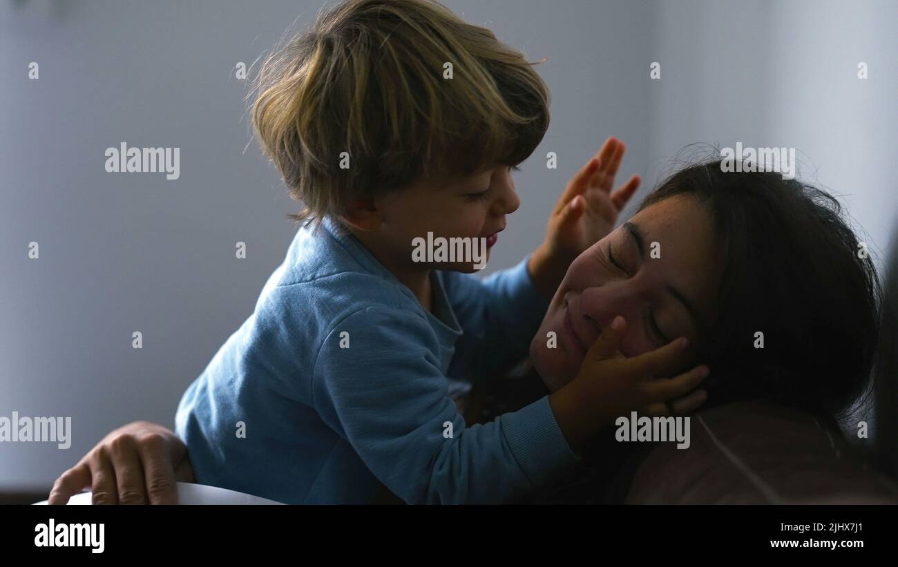 Little boy biting mother nose, real life authentic family moment at ...