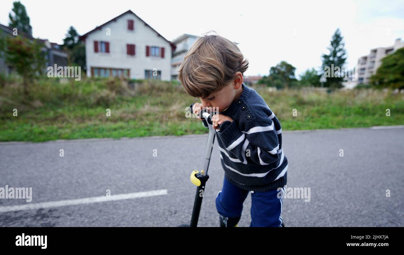 Little boy riding three wheeled scooter outdoors Stock Photo - Alamy