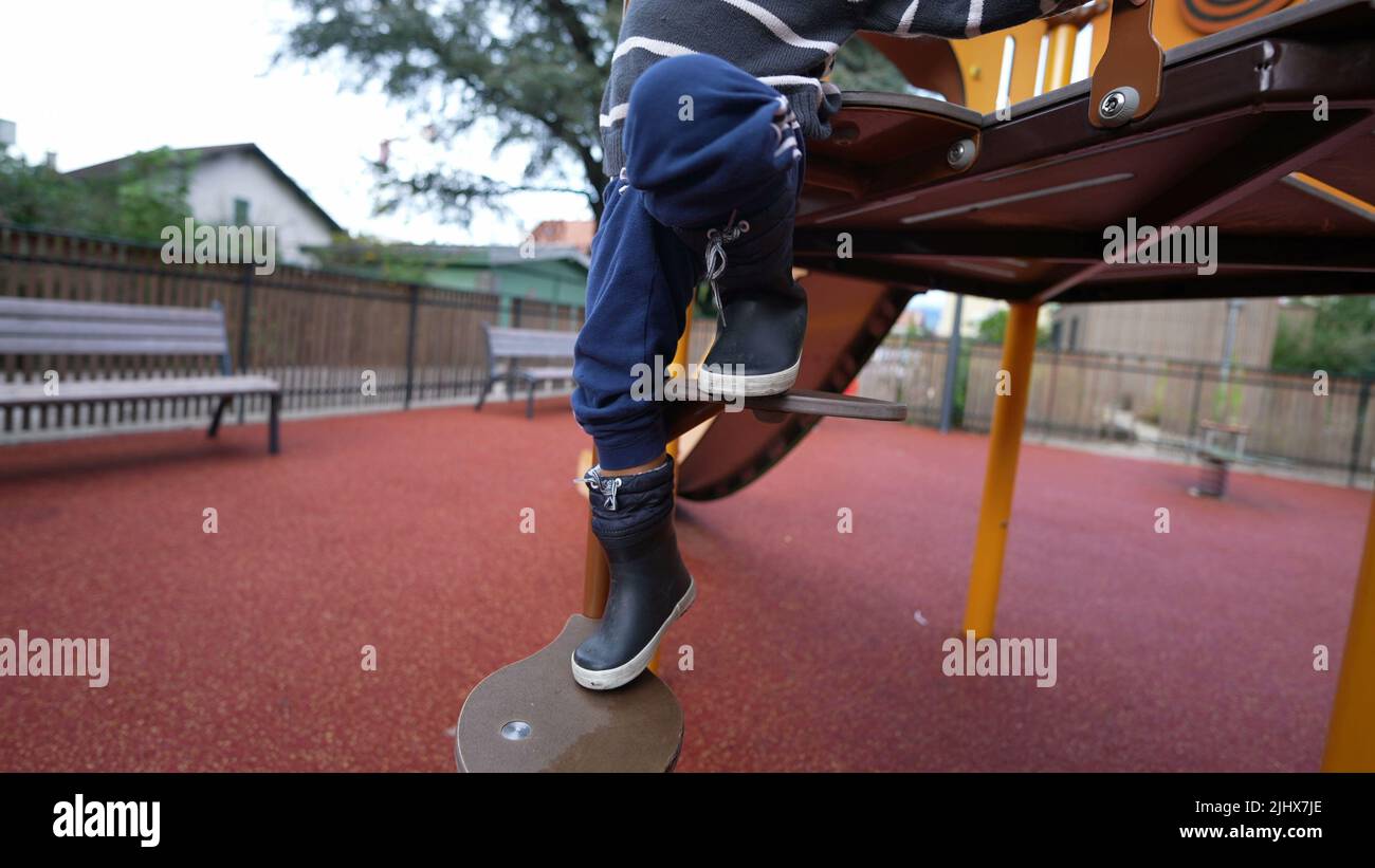 Little boy stepping down from playground structure steps equipment ...