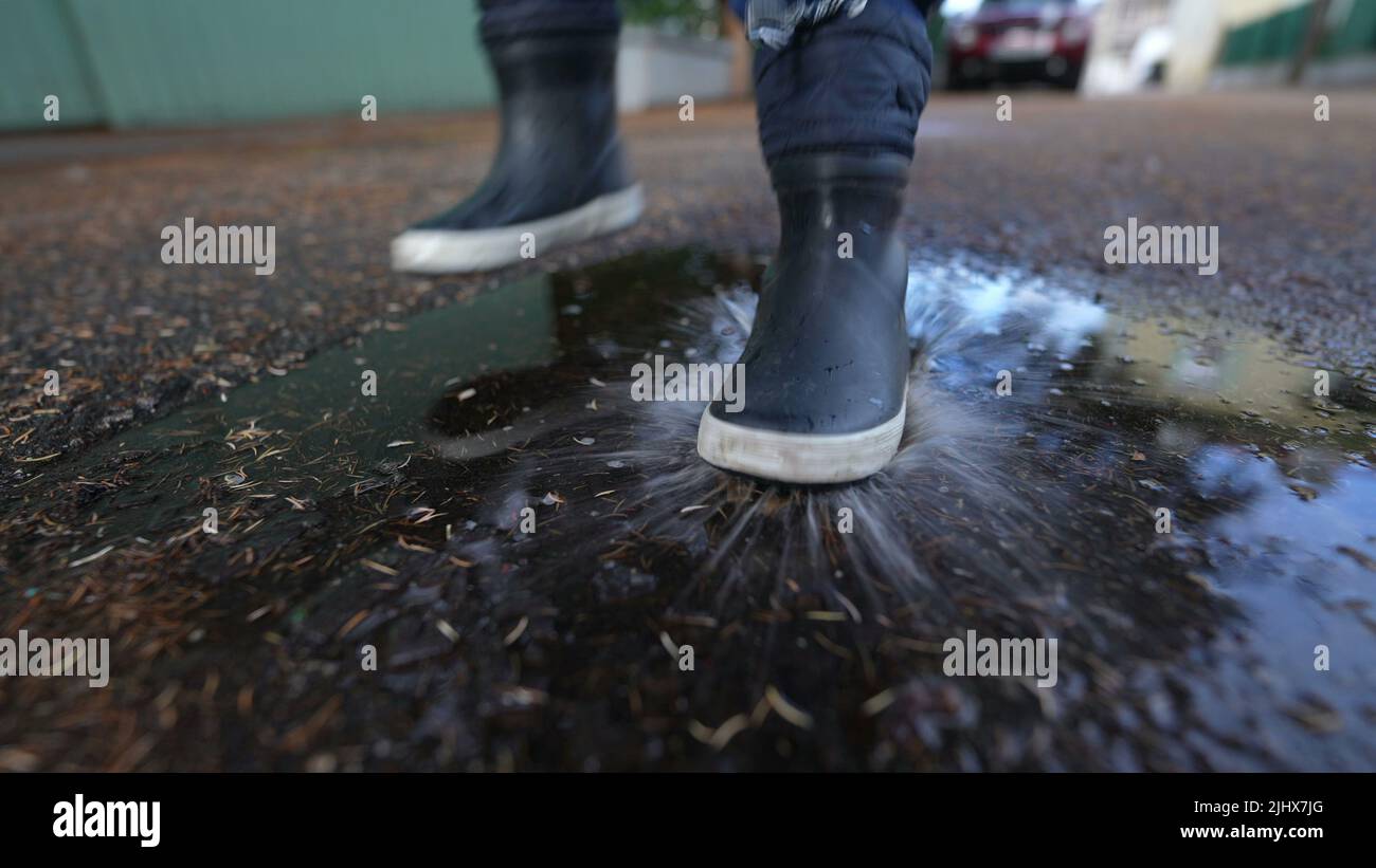 Little child jumping into puddle wearing boots Stock Photo - Alamy