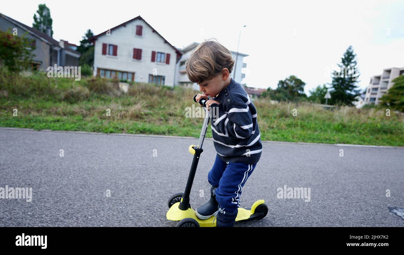 Little boy riding three wheeled scooter outdoors Stock Photo - Alamy