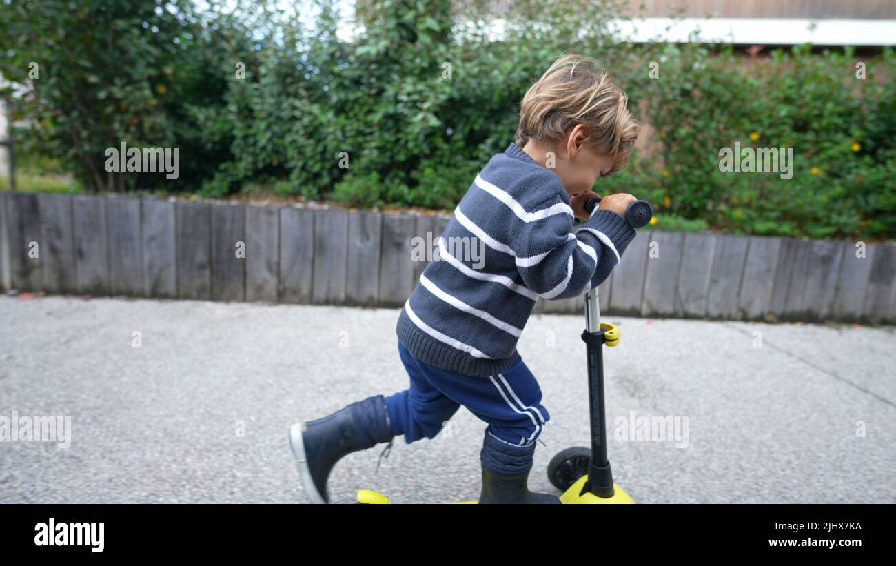 Little boy riding three wheeled scooter outdoors Stock Photo - Alamy