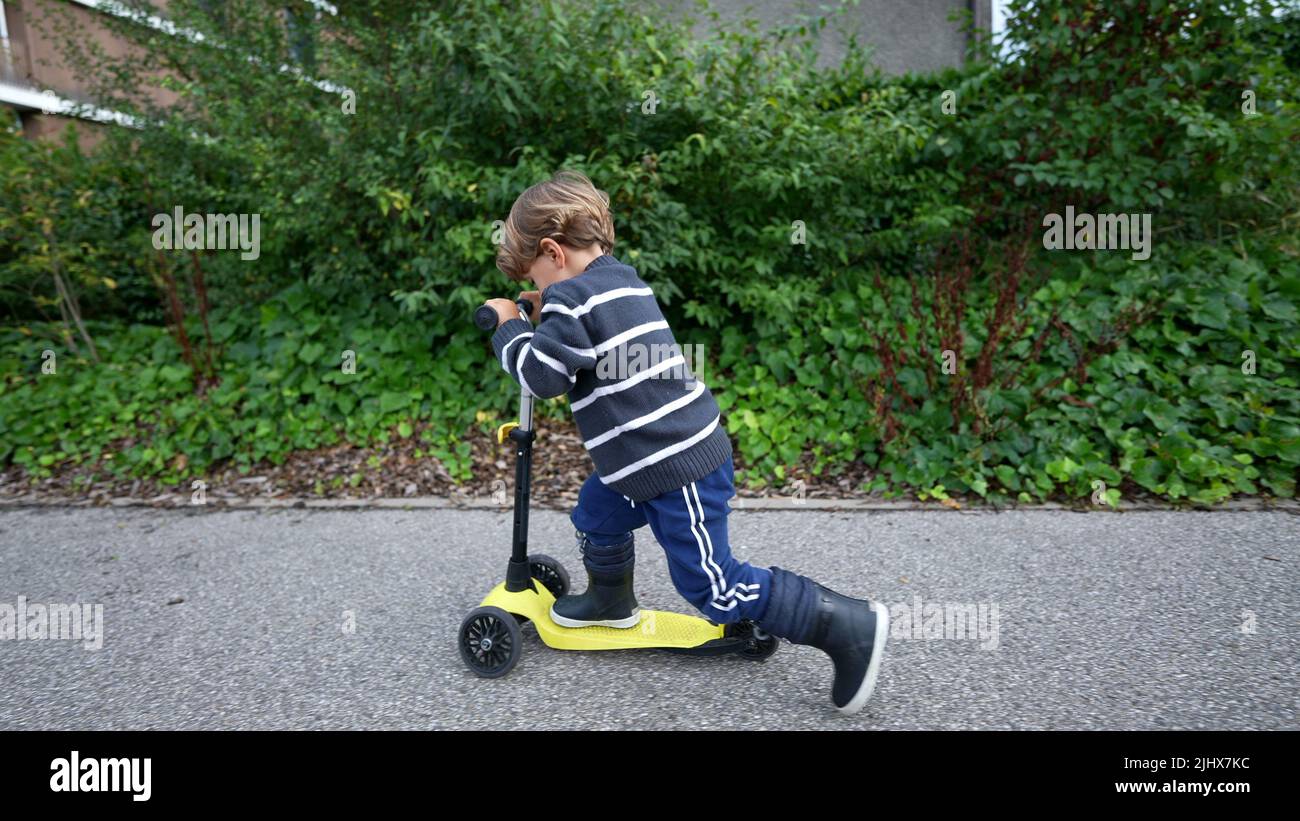 Little boy riding three wheeled scooter outdoors Stock Photo - Alamy