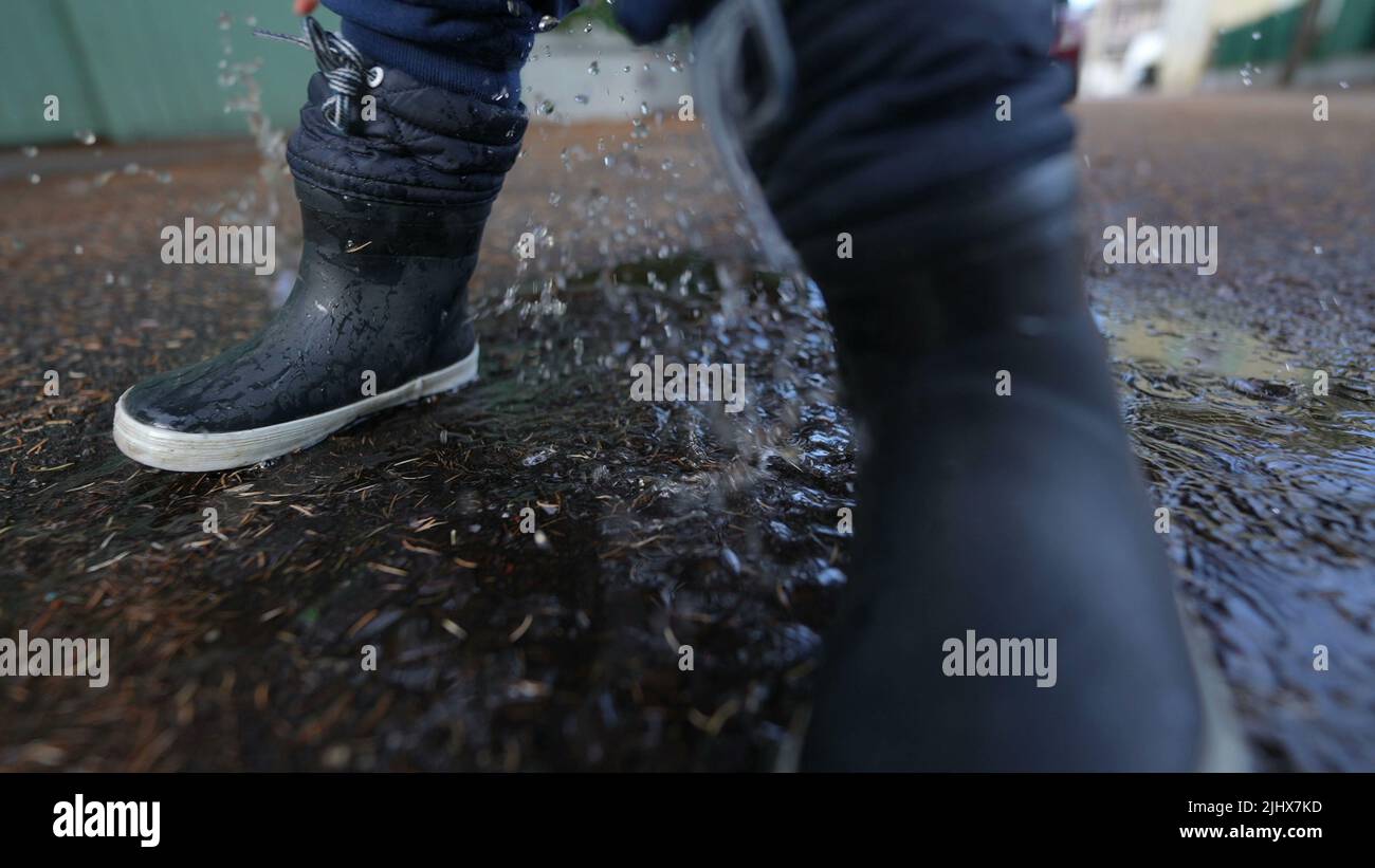 Little child jumping into puddle wearing boots Stock Photo - Alamy