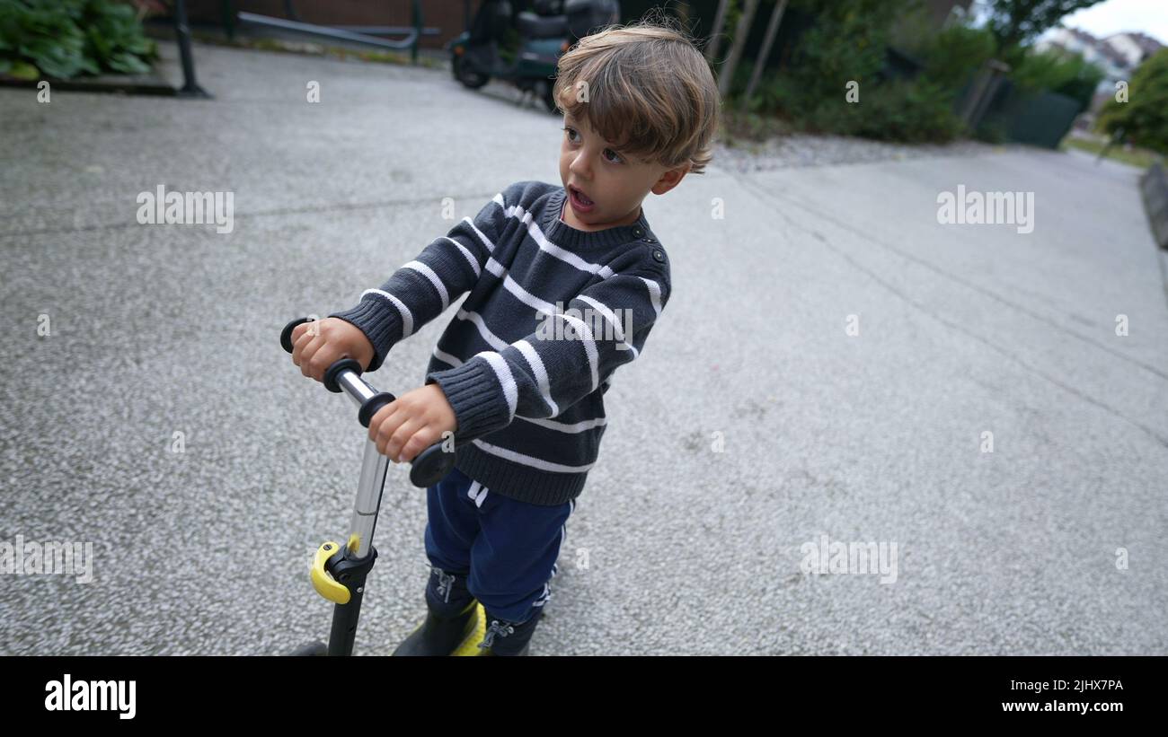 Child rides toy scooter outside Stock Photo - Alamy