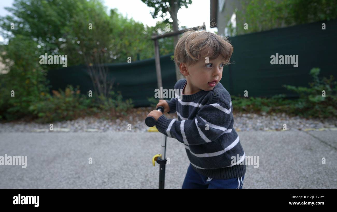 Healthy child rides three wheeled scooter, kid pushing scooter Stock ...
